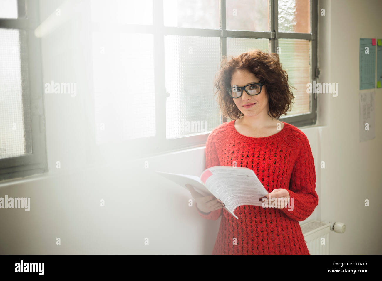 Young woman reading document at the window Stock Photo - Alamy