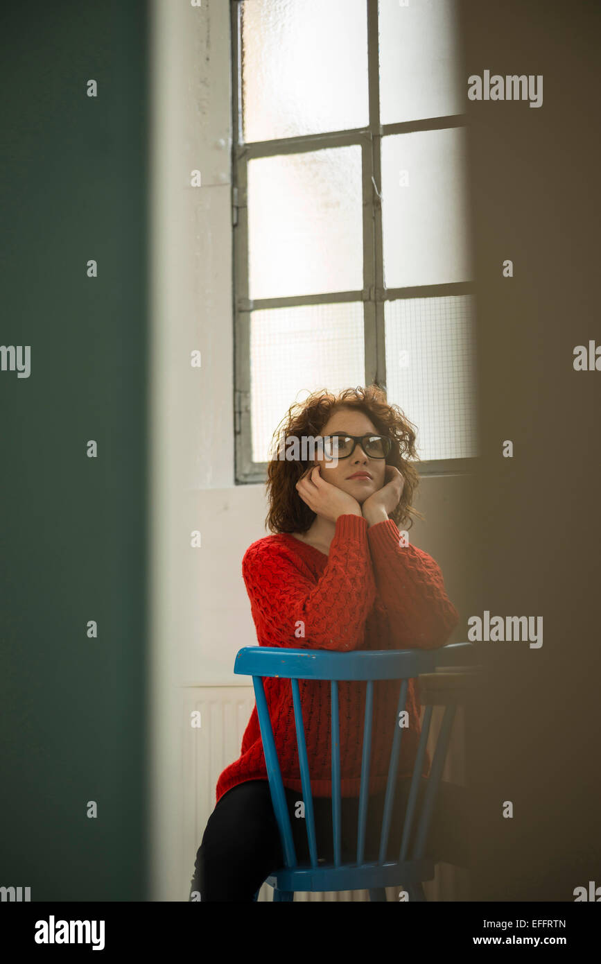 Young woman sitting on chair thinking Stock Photo - Alamy