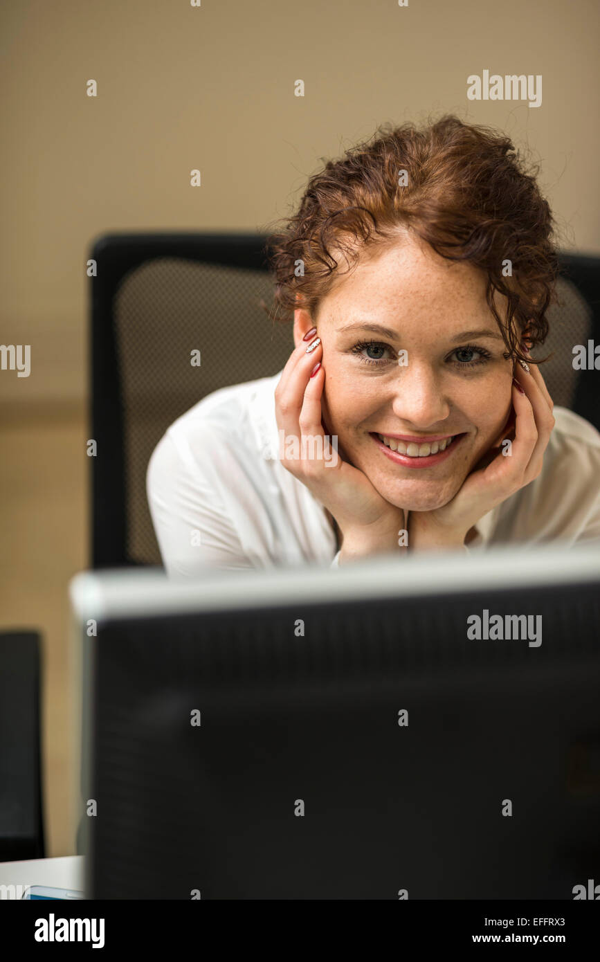 Portrait of smiling young woman at desk Stock Photo - Alamy