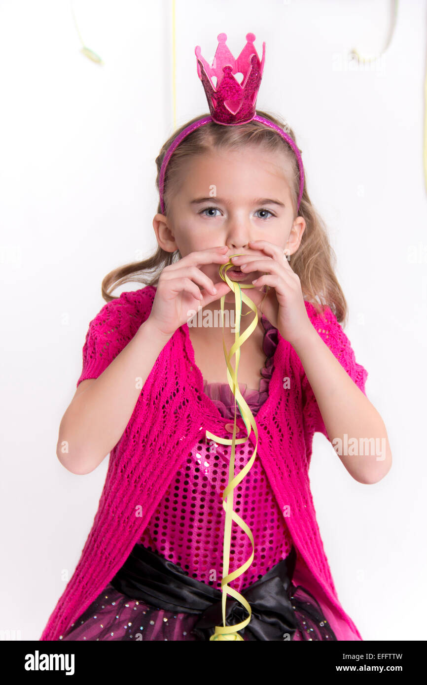 Portrait of little girl masquerade as a princess blowing streamer Stock ...