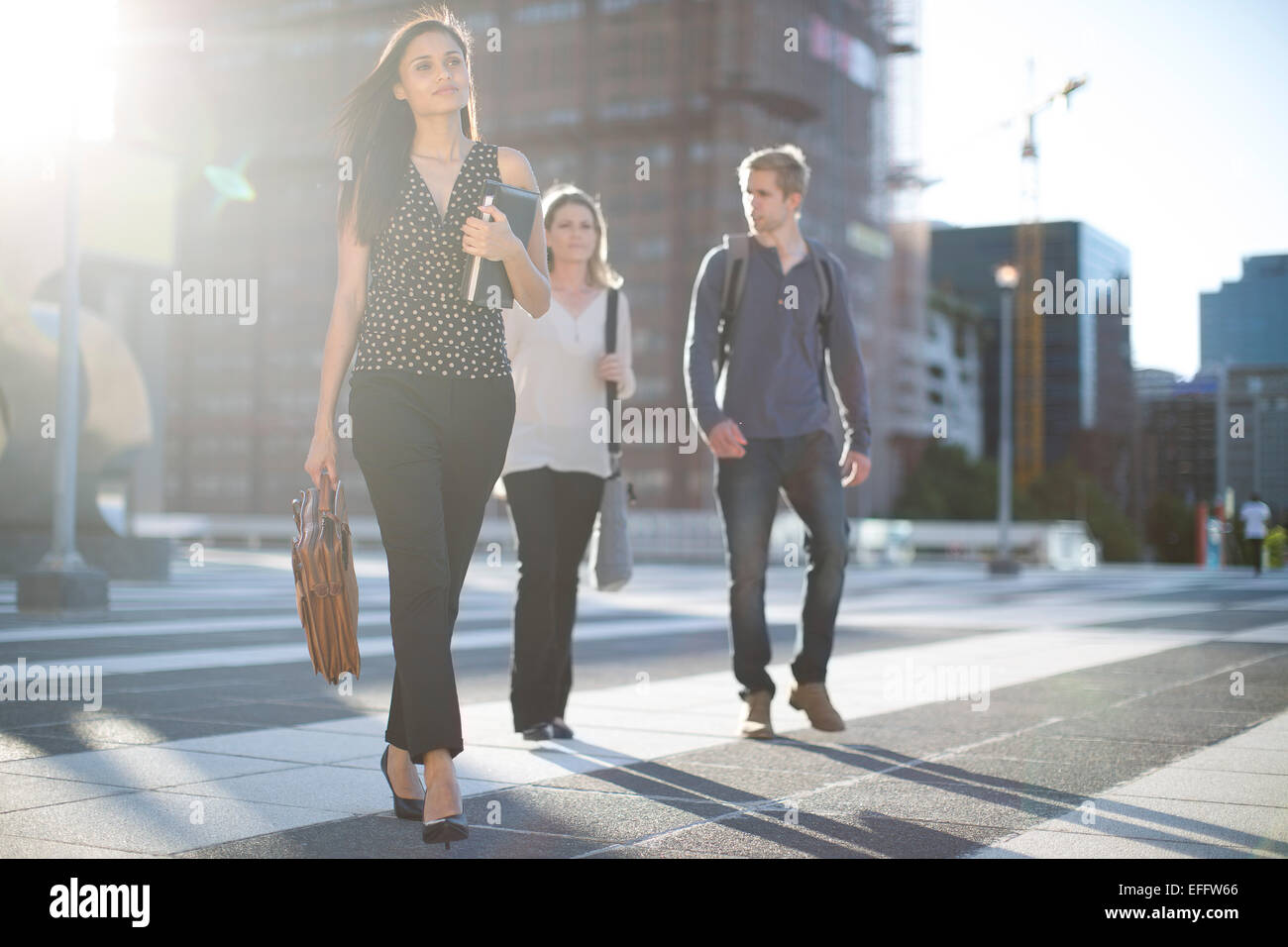 Three people walking on city square Stock Photo - Alamy