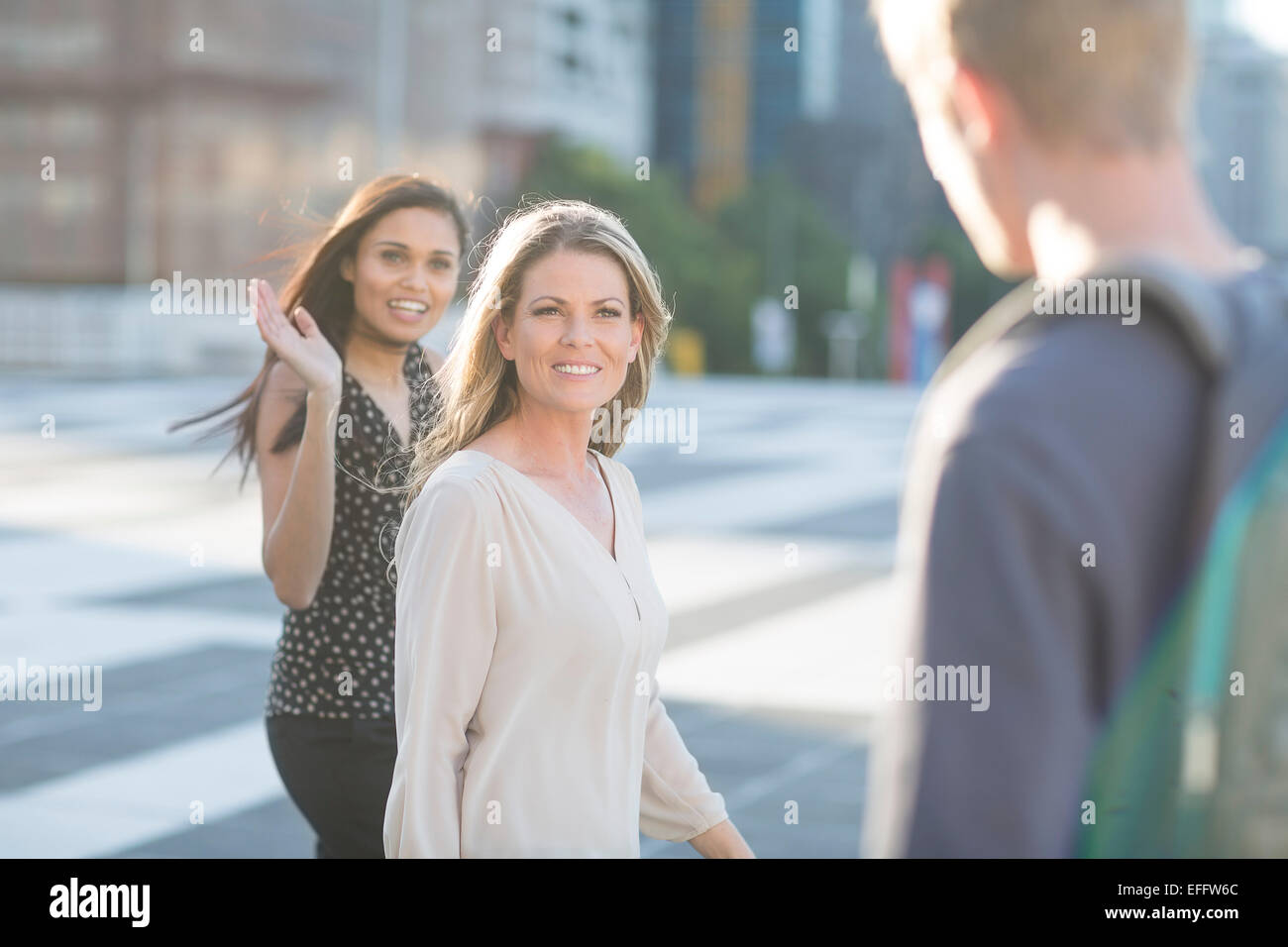 Three people meeting on city sqare Stock Photo - Alamy