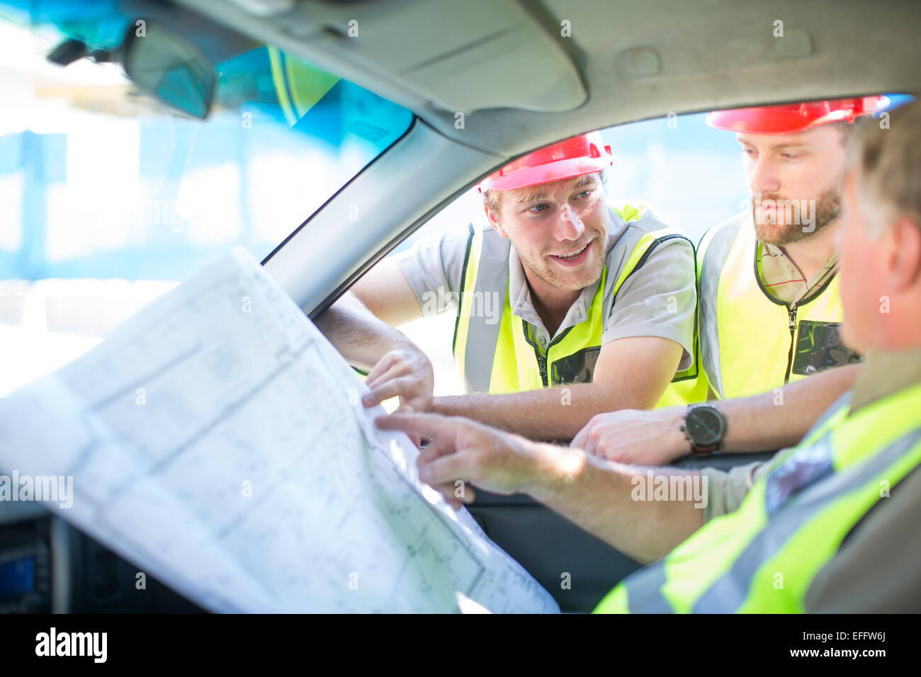 Builders discussing construction plan in car Stock Photo - Alamy