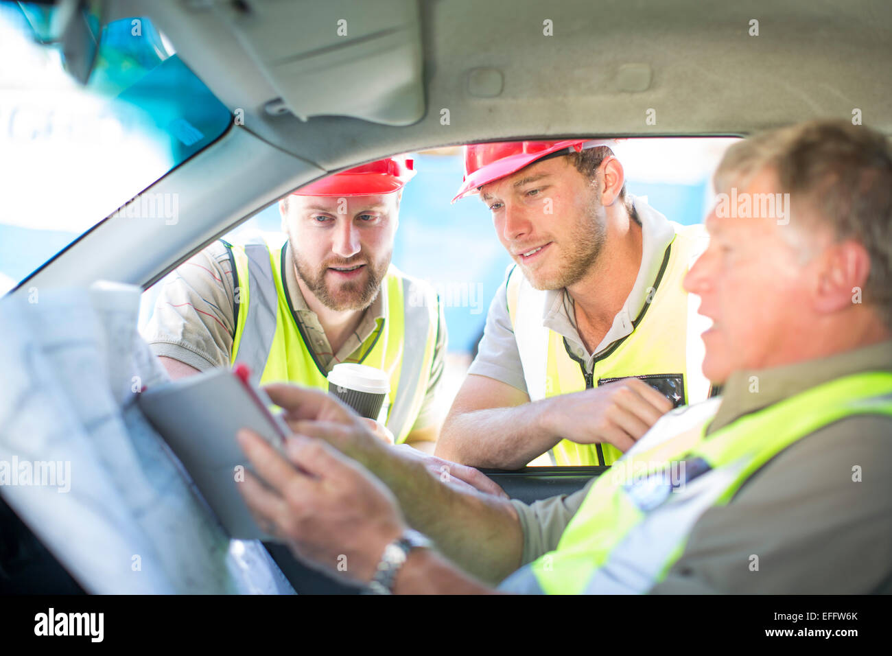 Builders discussing construction plan in car Stock Photo - Alamy