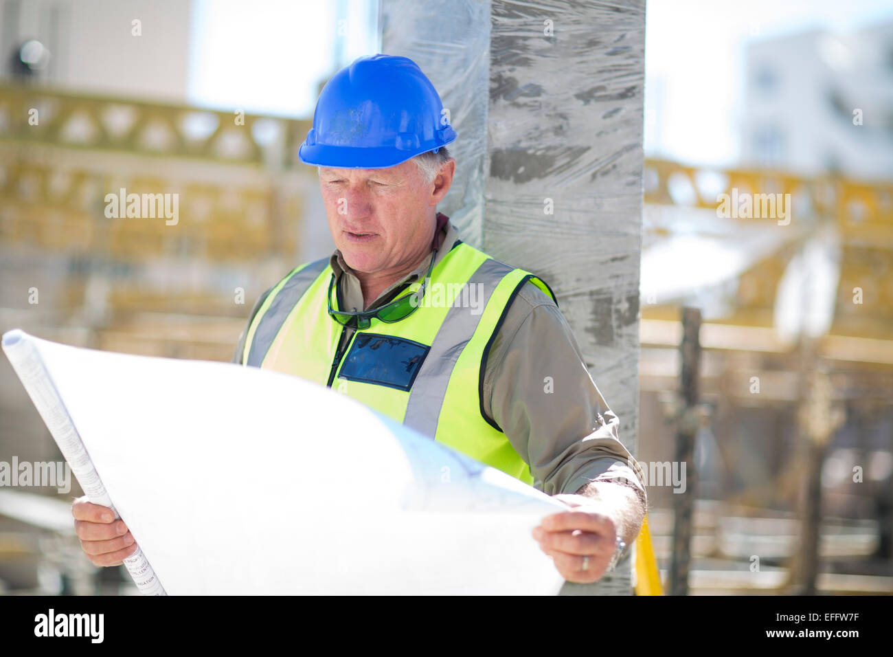Construction worker reading building plan in construction site Stock ...