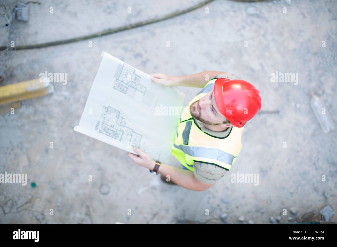 Construction worker holding plan at construction site Stock Photo - Alamy