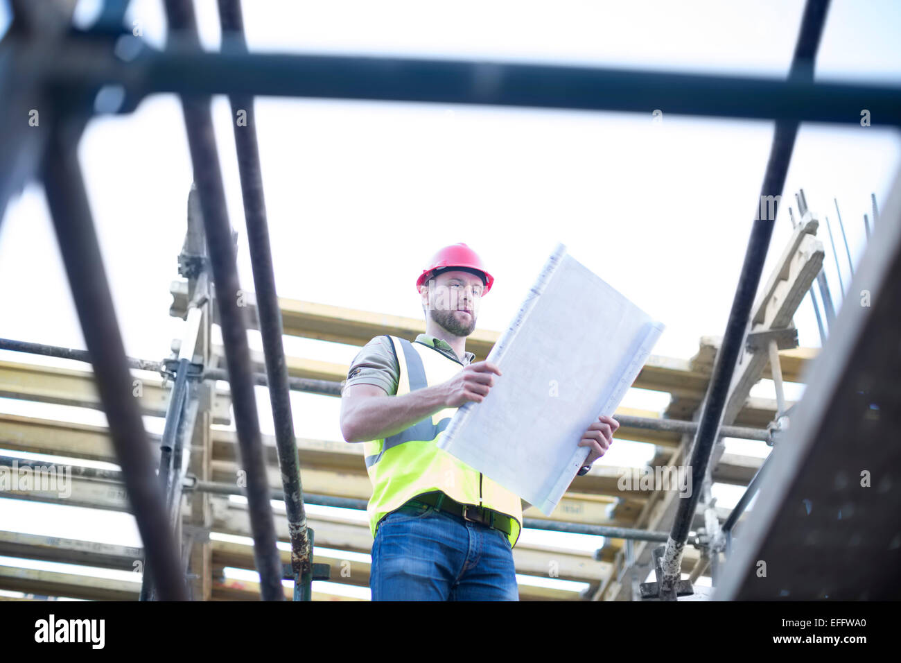 Construction worker reading plan at construction site Stock Photo - Alamy
