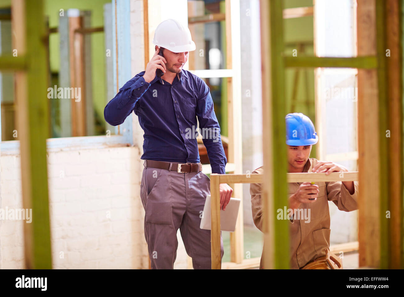Construction worker and foreman measuring wood frame Stock Photo - Alamy