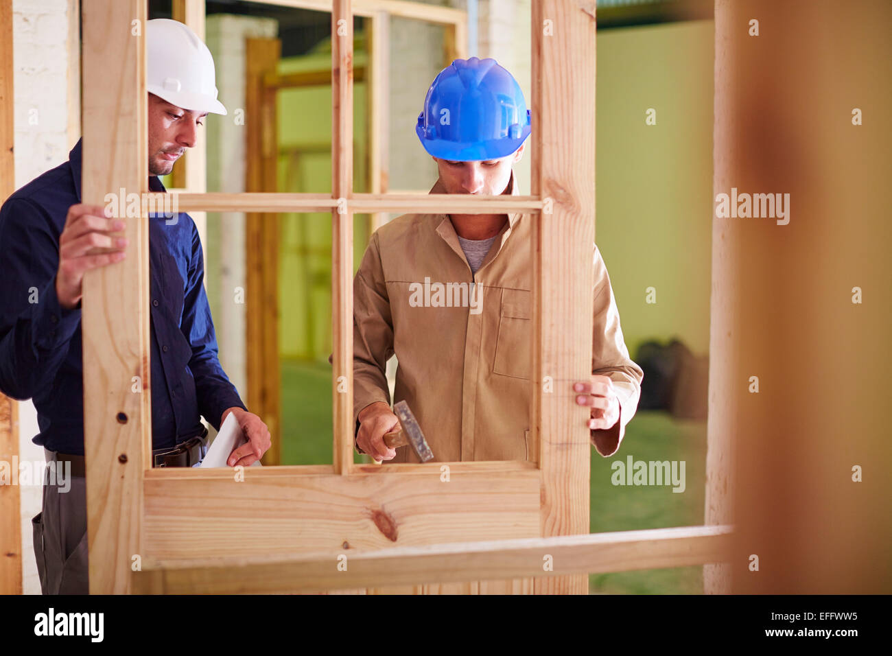 Construction worker and foreman working with wood frame Stock Photo - Alamy
