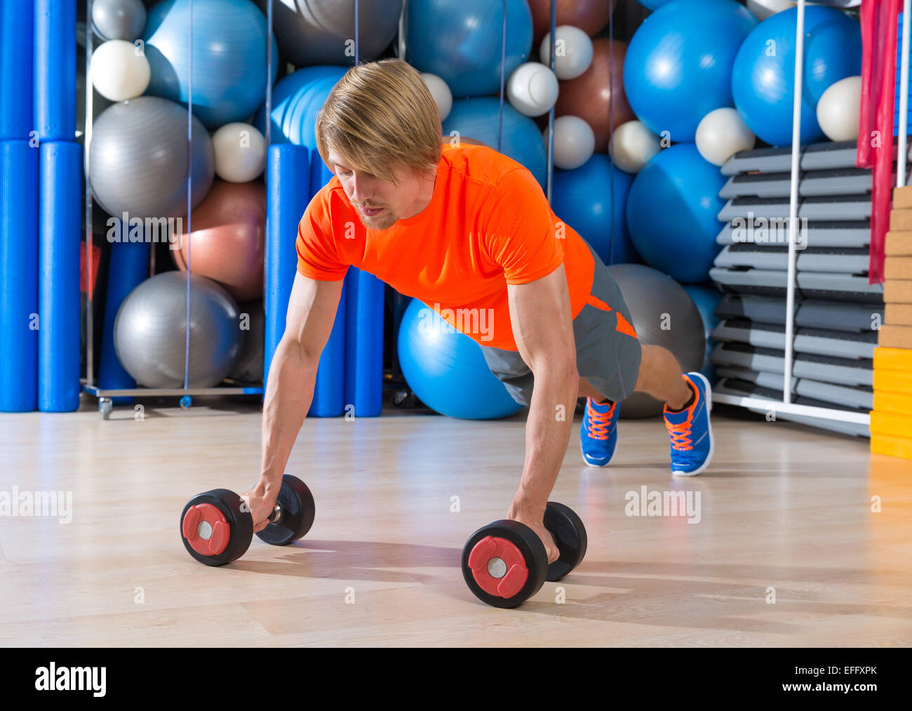 Blond man gym push-up strength pushup exercise with dumbbells workout ...
