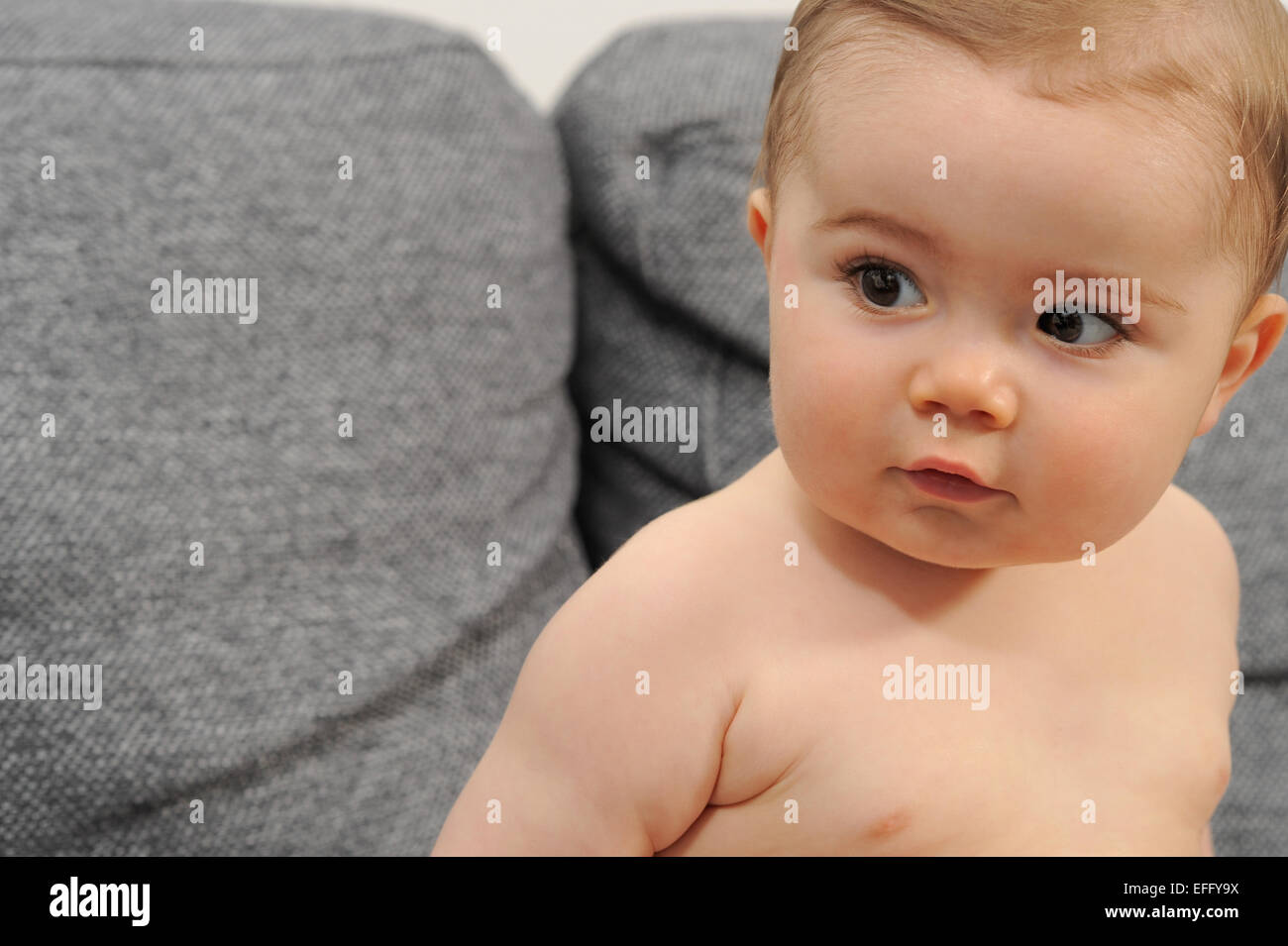 Small child - Baby sitting on sofa Stock Photo - Alamy