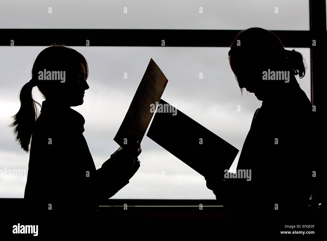 Two female pupils read from sheets at school Stock Photo - Alamy