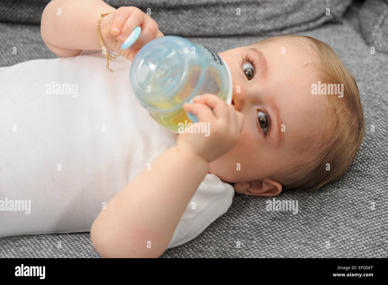 Small child - Baby sitting on sofa drinking Stock Photo - Alamy
