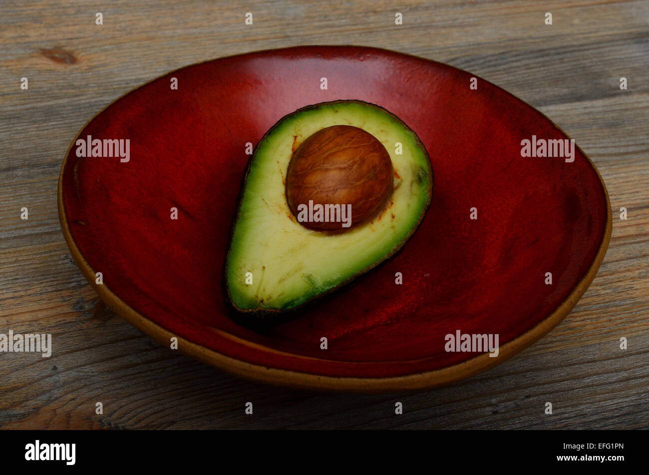 fresh avocado half on a red ceramic bowl Stock Photo - Alamy