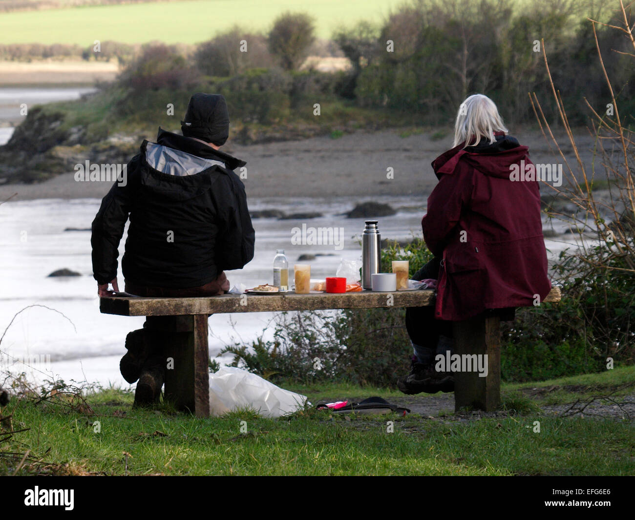 Couple having a winter picnic along the Camel Estuary near Wadebridge ...