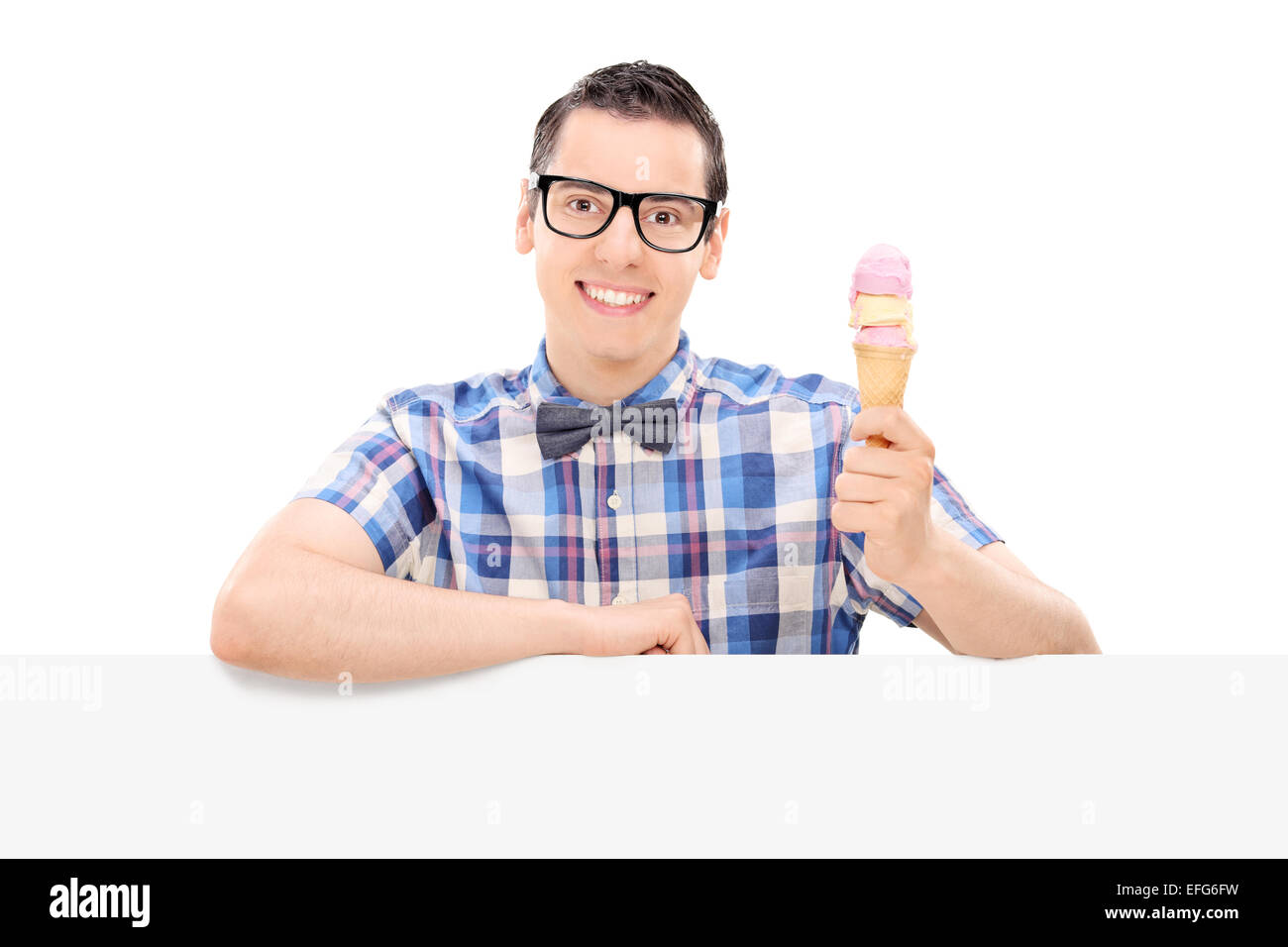 Cheerful guy holding an ice cream behind a panel isolated on white ...