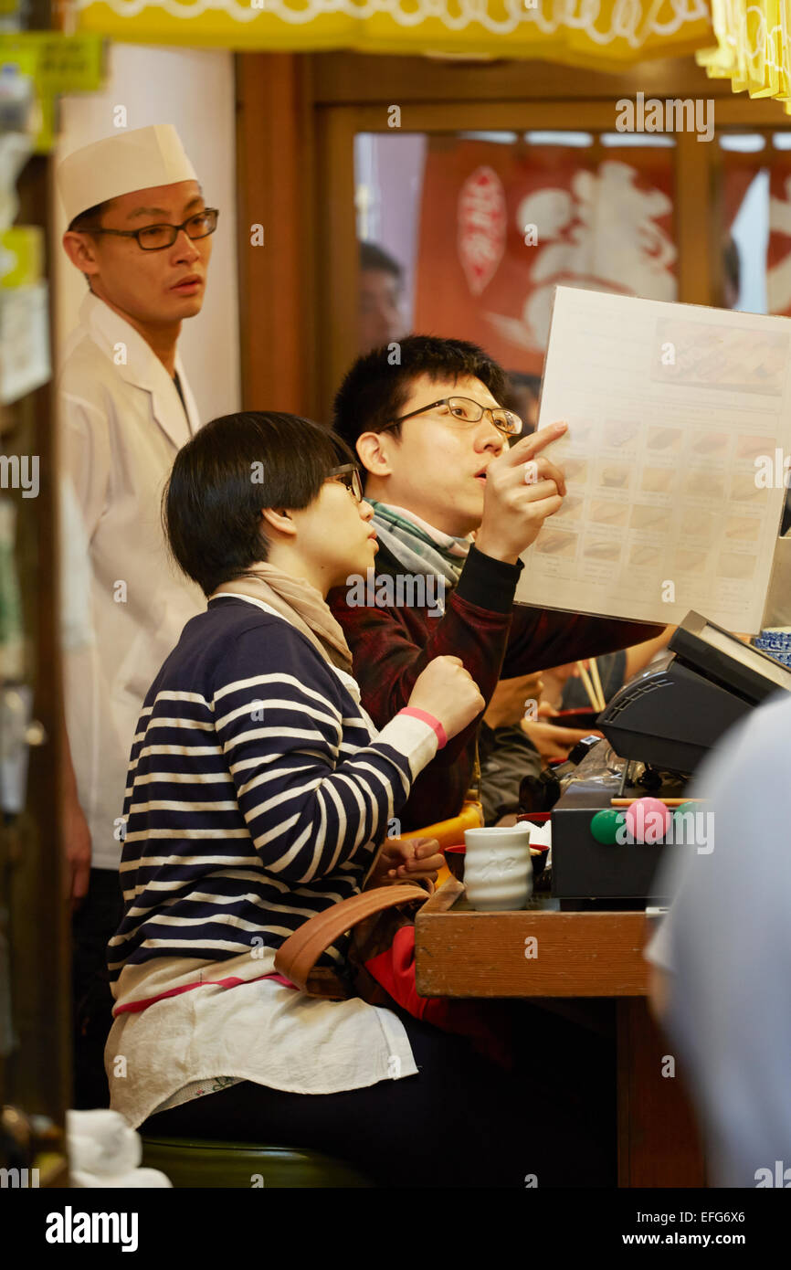 People in sushi restaurant looking at menu , Fish Market, Tsukiji ...