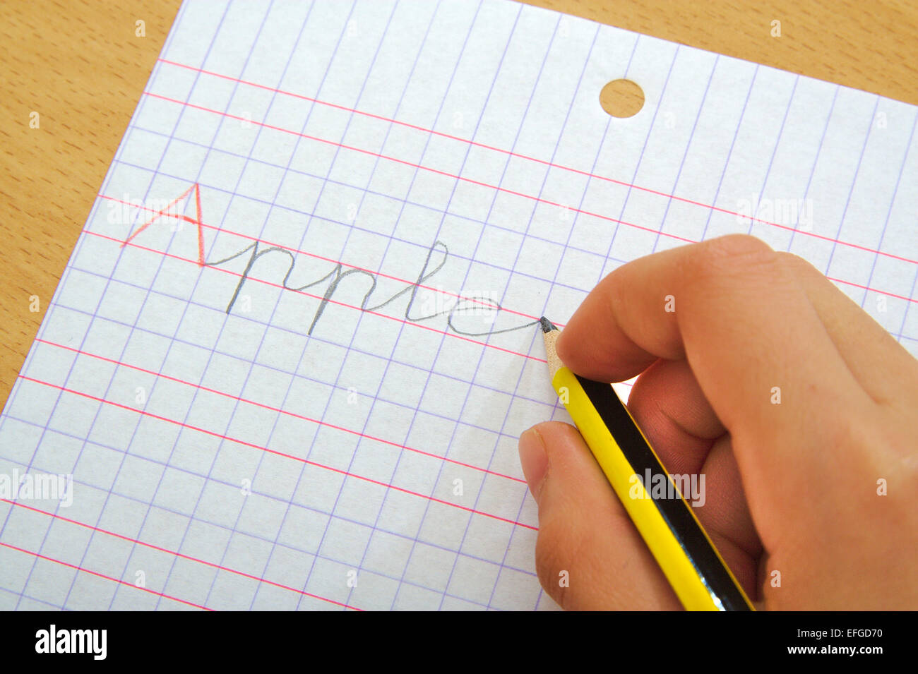 Closeup of the hand of a child writing apple word with a pencil. School ...