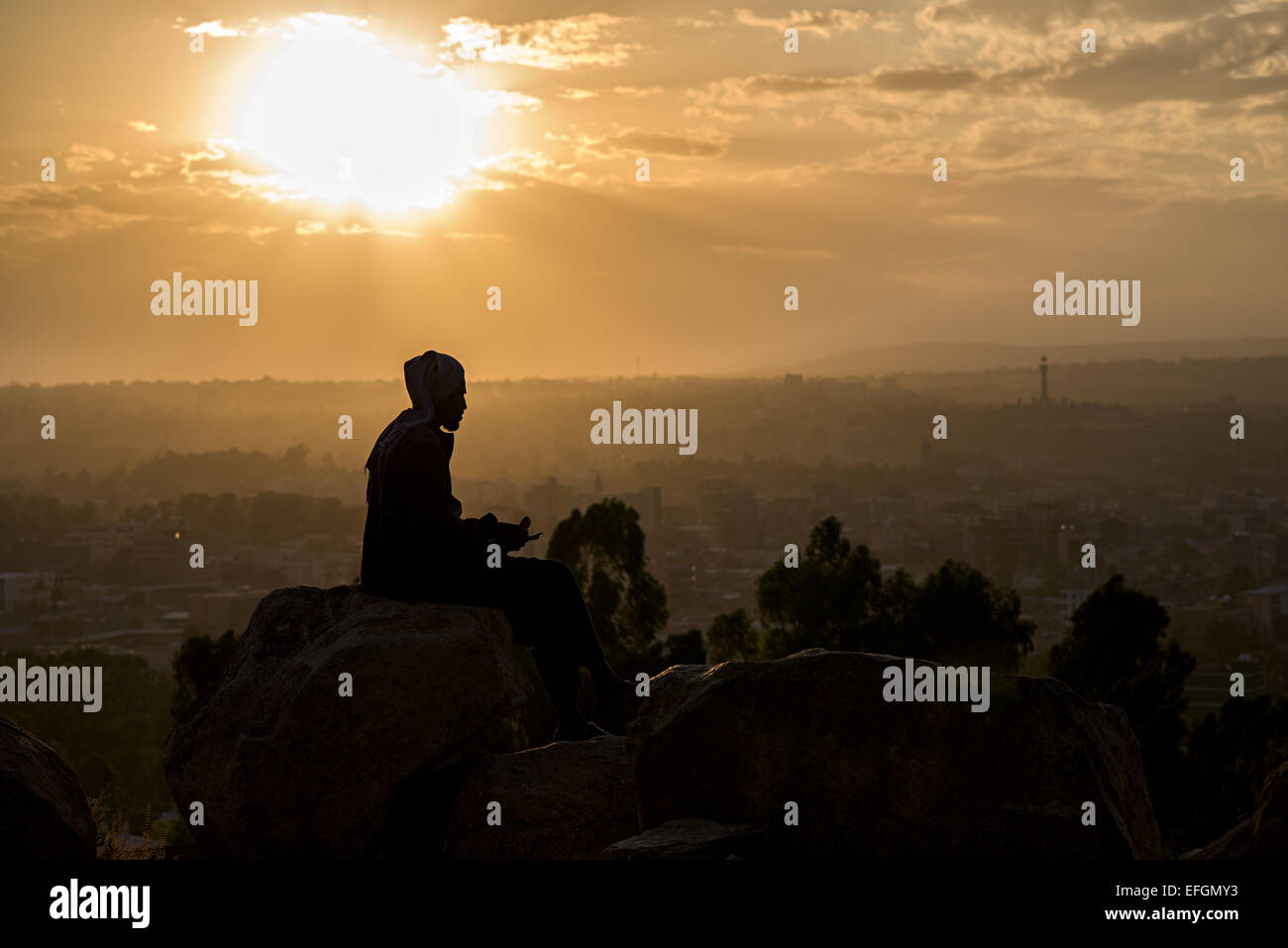An old man sitting on a rock and watching the city from above Stock ...