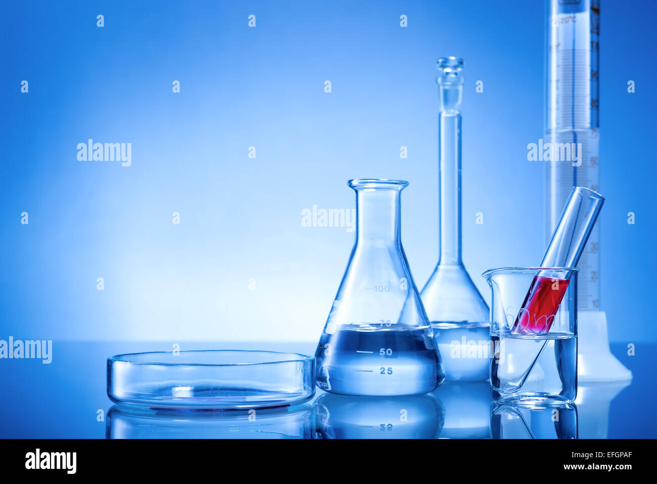 Laboratory equipment, glass flasks, pipettes, red liquid on blue ...