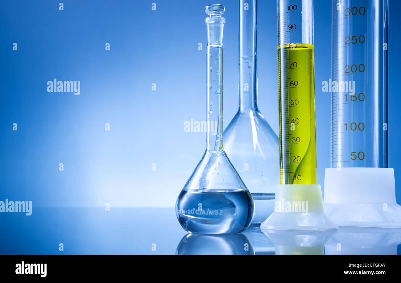 Laboratory equipment, bottles, flasks with yellow liquid on blue ...
