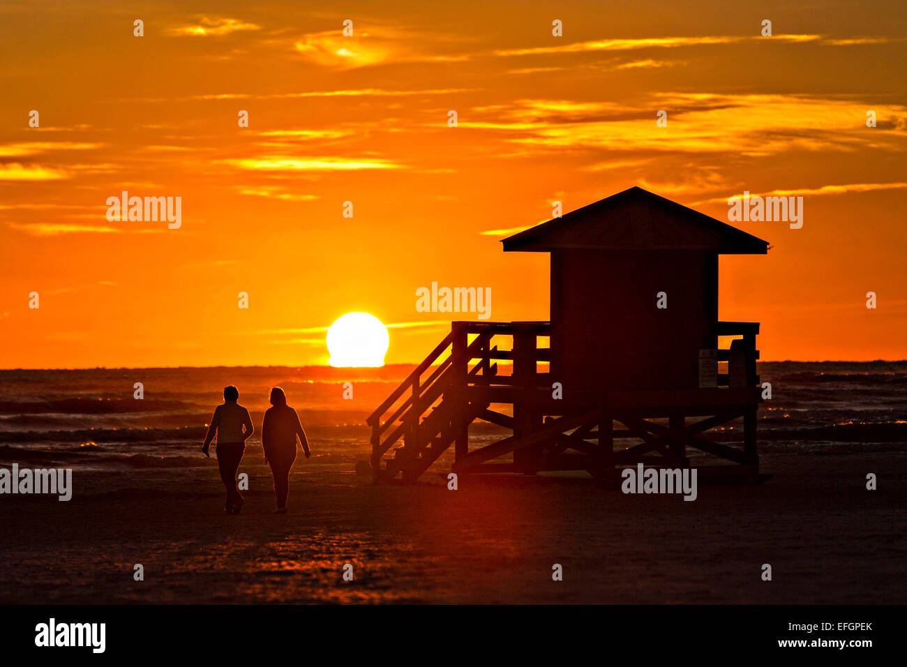A couple is silhouetted by the sunset over Siesta Key beach in Sarasota ...