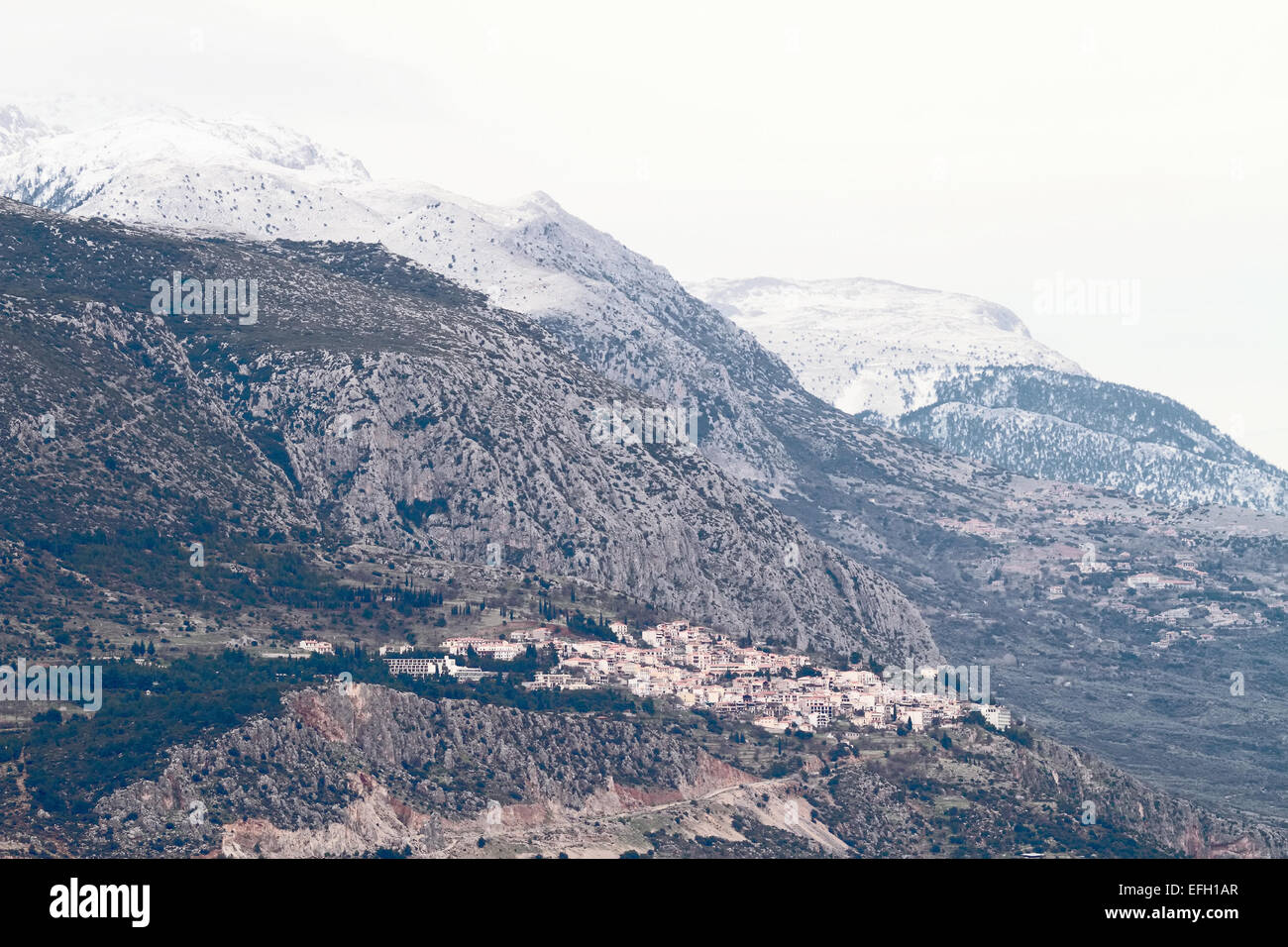 The village of the ancient site of Delphi below the snow-capped peaks ...