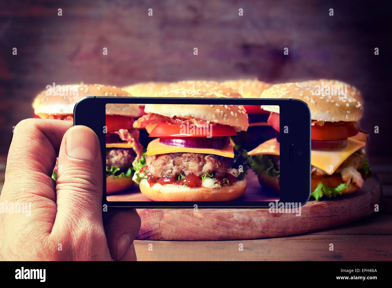 Man shooting with his cell phone camera big and tasty burgers.Selective ...