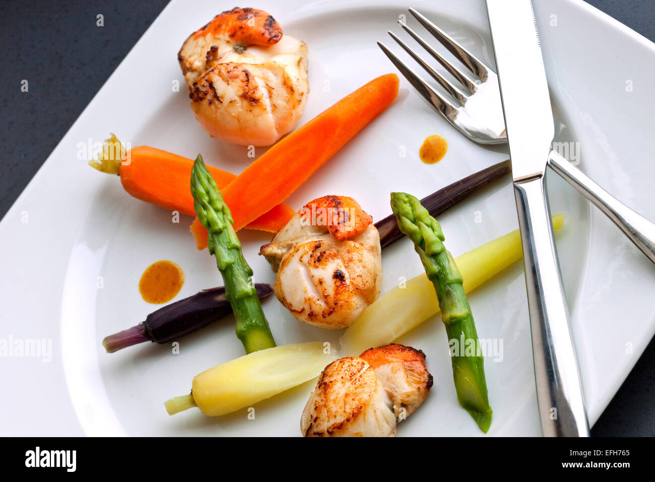 Scallops and vegetables on a plate Stock Photo - Alamy