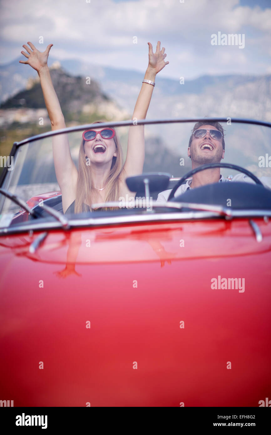 Young couple having fun in in a convertible red sports car in the South ...