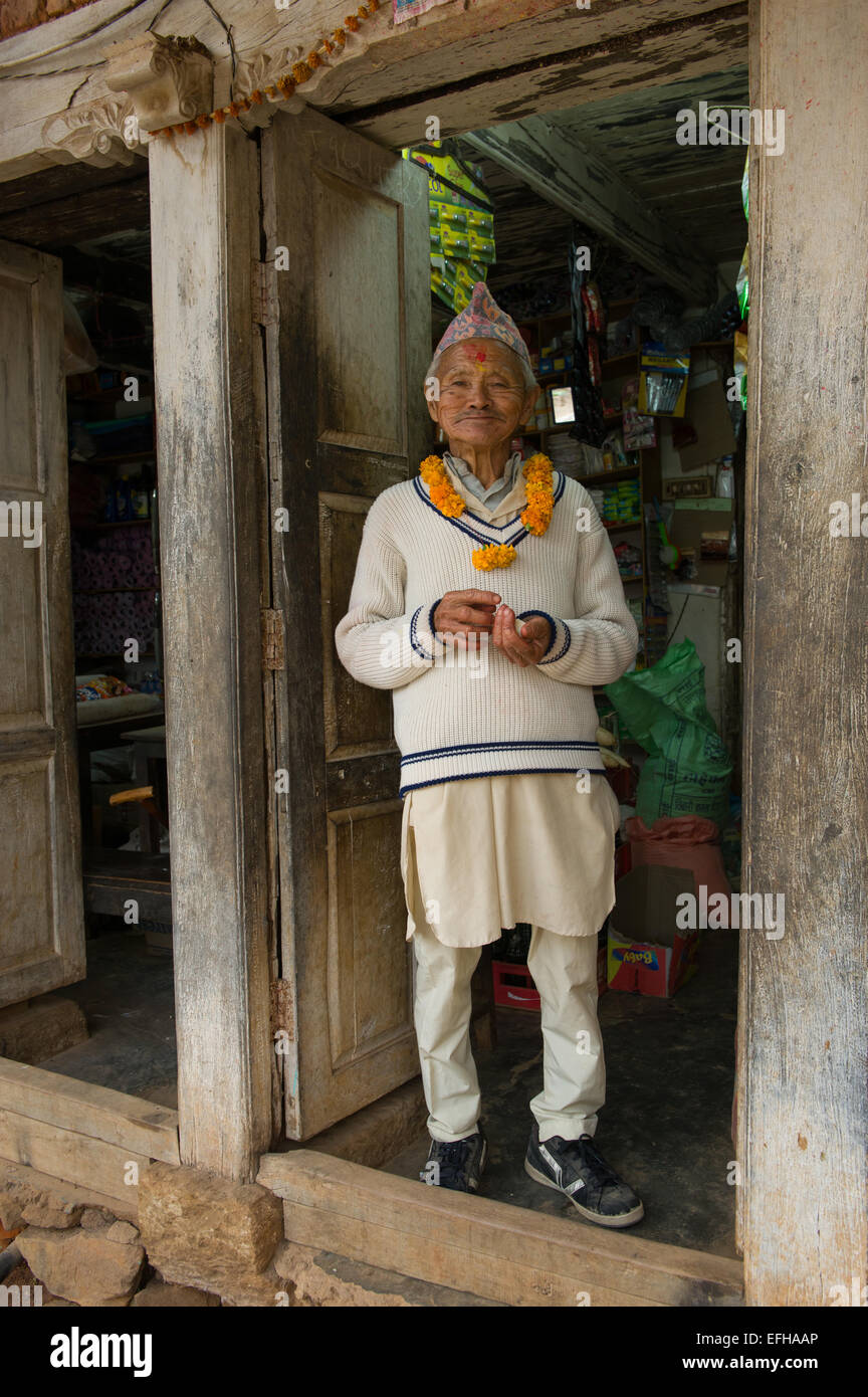 Old Newari man in a traditional Newari hat, standing in his shophouse ...
