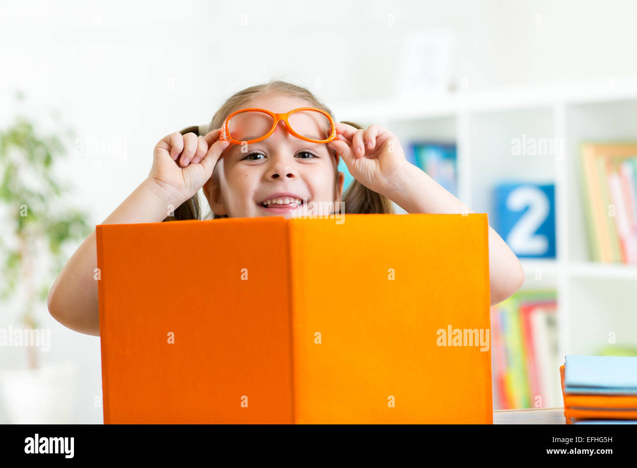 clever child girl behind of open book indoor Stock Photo - Alamy