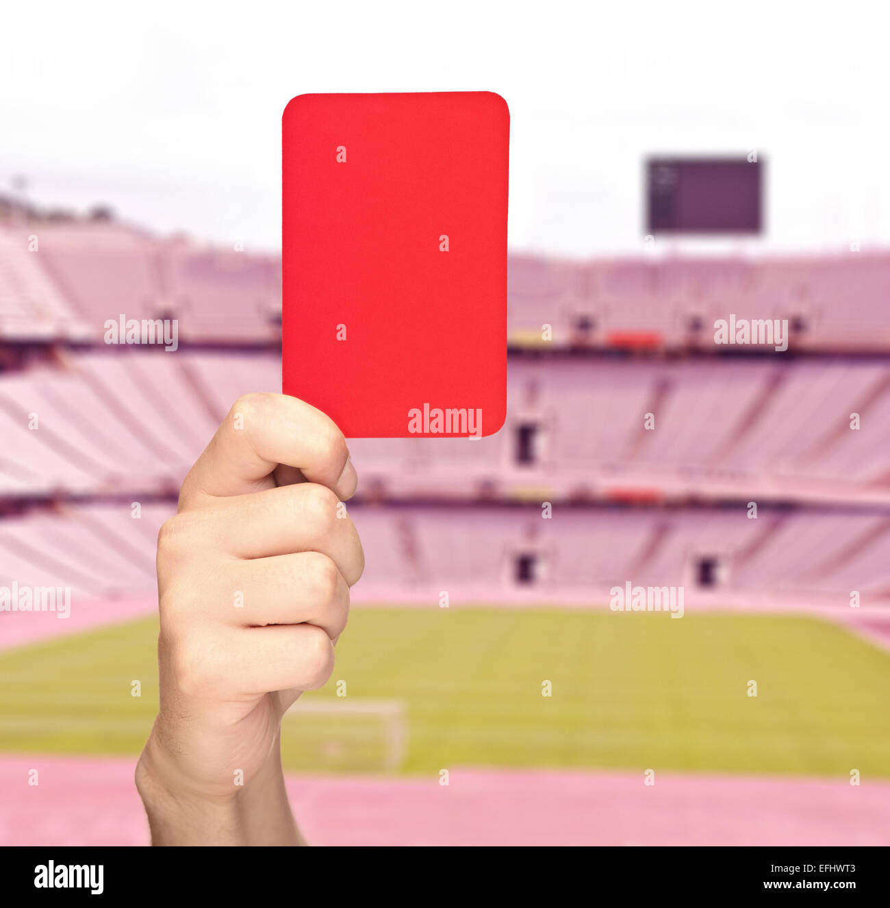 Hand holding a red card in front of an empty stadium shot with tilt and ...