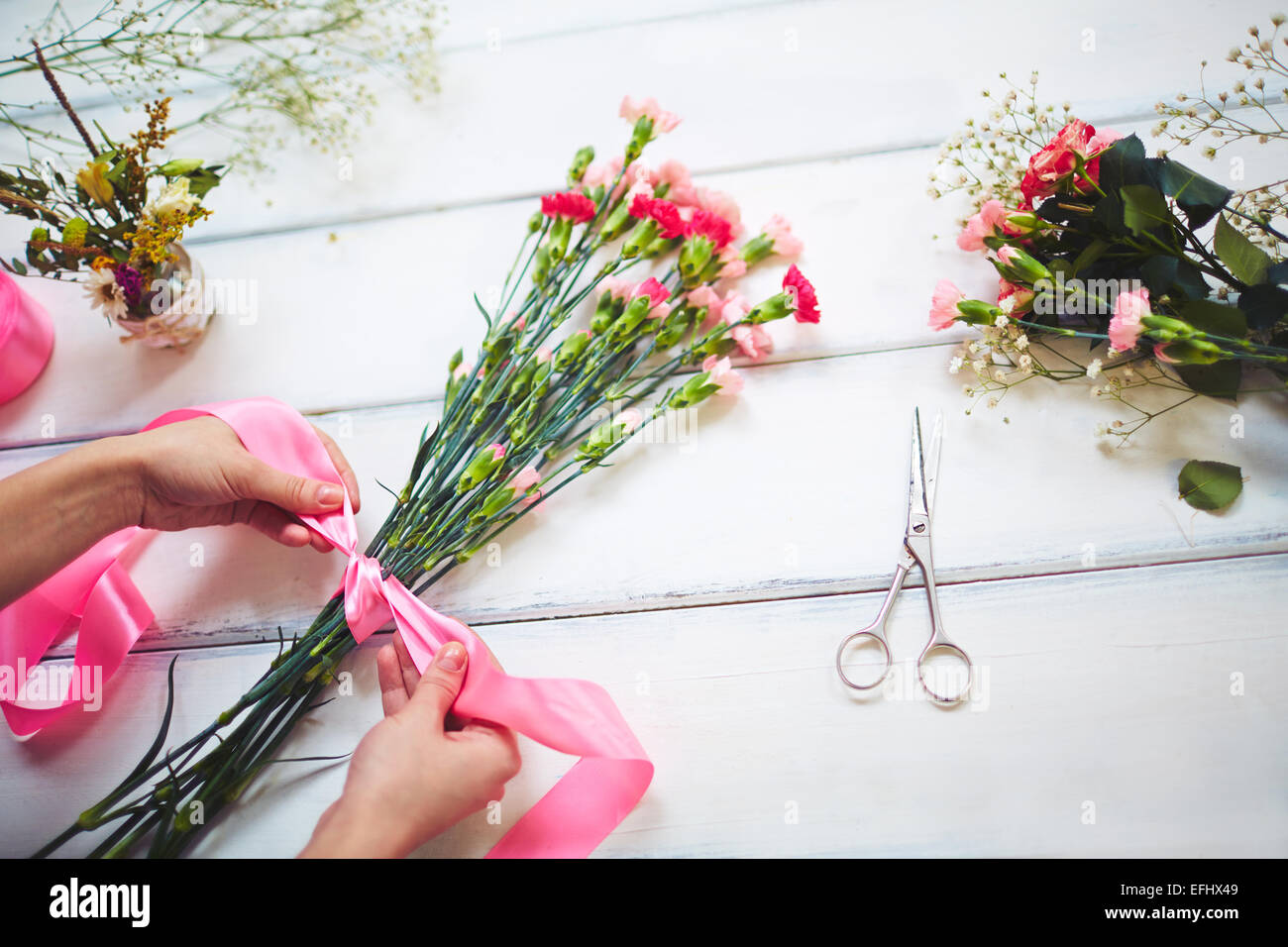 Female hands tying carnation bouquet with silk ribbon Stock Photo - Alamy