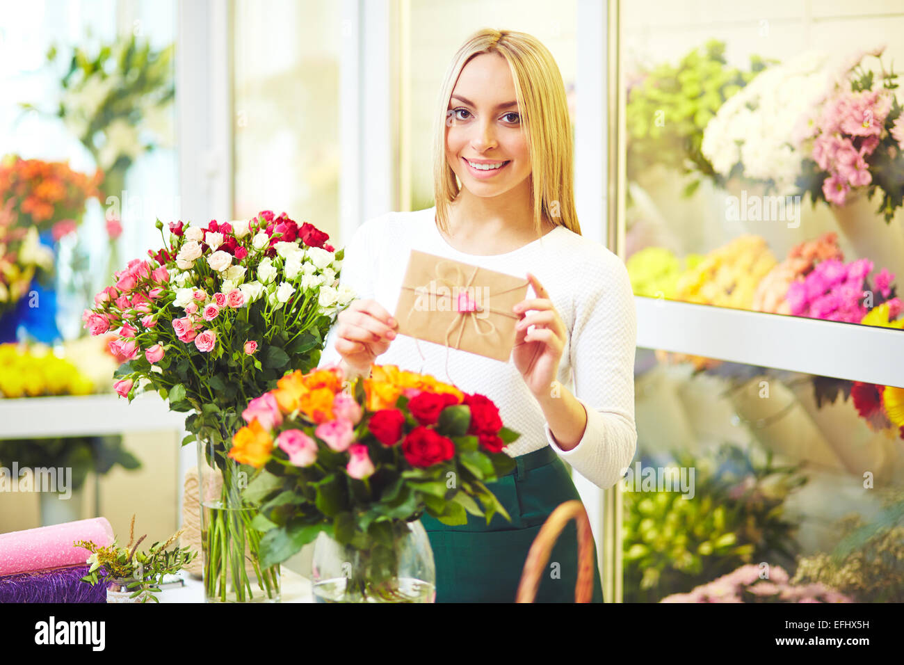 Happy florist with congratulation message in small envelope and fresh ...