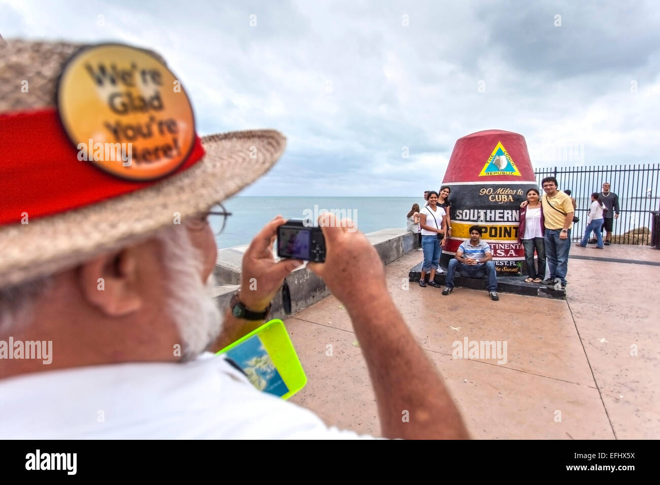 Tourists and local tourist guide at the Southernmost Point Landmark ...