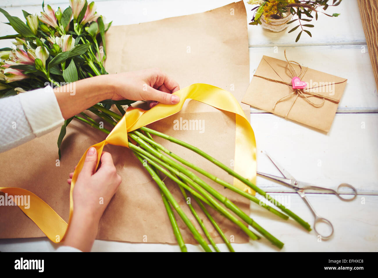 Female florist tying up fresh flowers with silk ribbon Stock Photo - Alamy