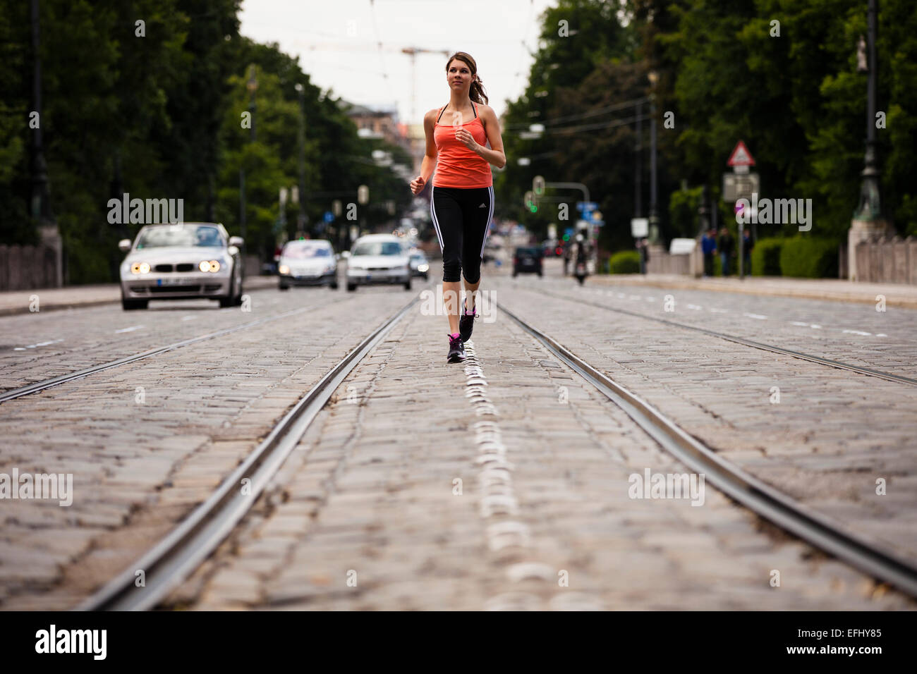 Young woman jogging over Maximilian bridge, Munich, Bavaria, Germany ...