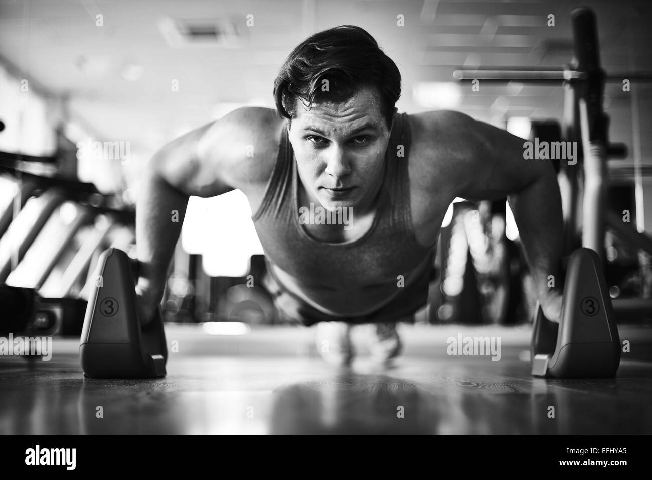 Handsome athlete doing difficult exercise in gym Stock Photo - Alamy
