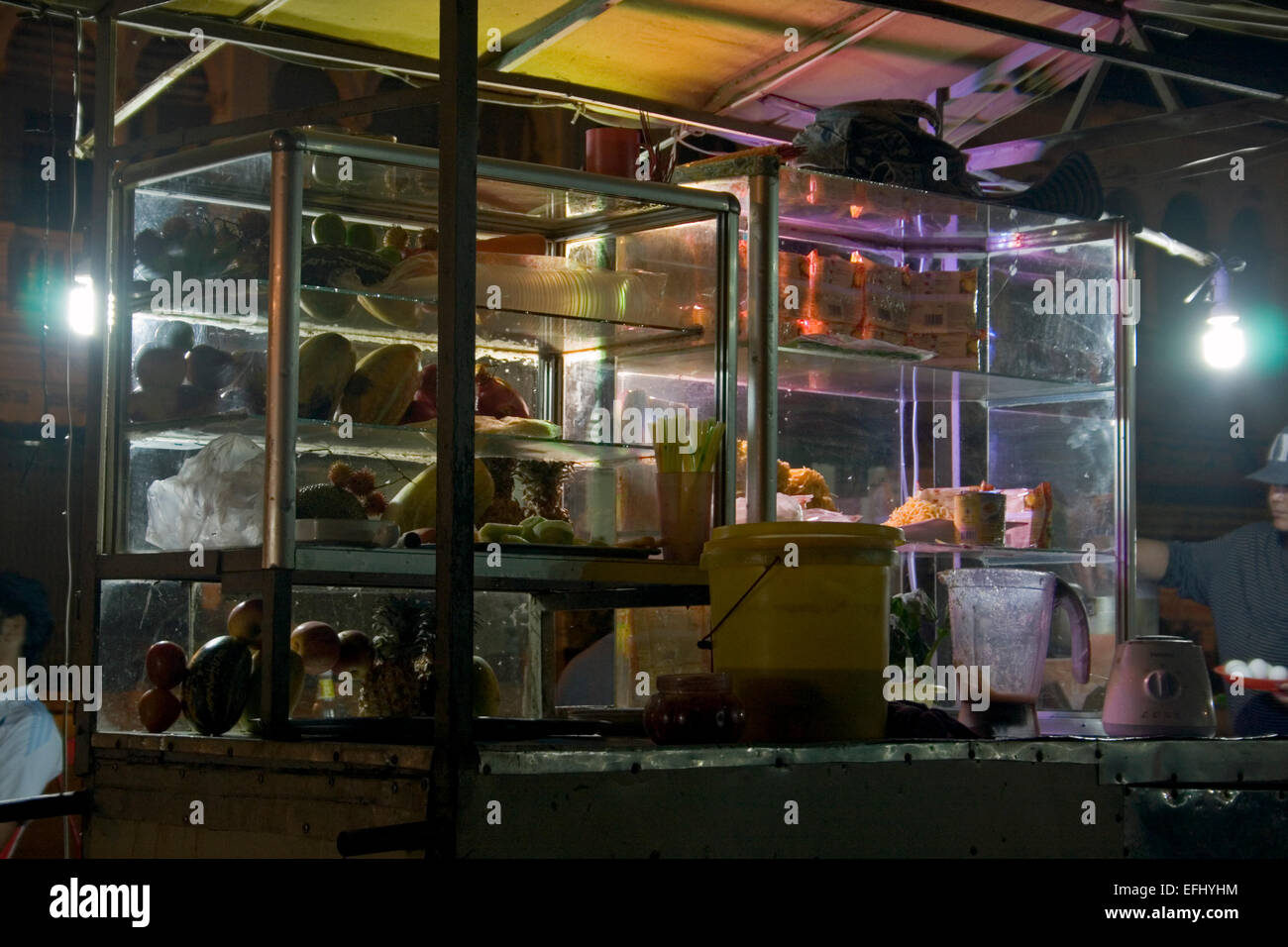 A street food cart serves assorted food at night on a city street in ...
