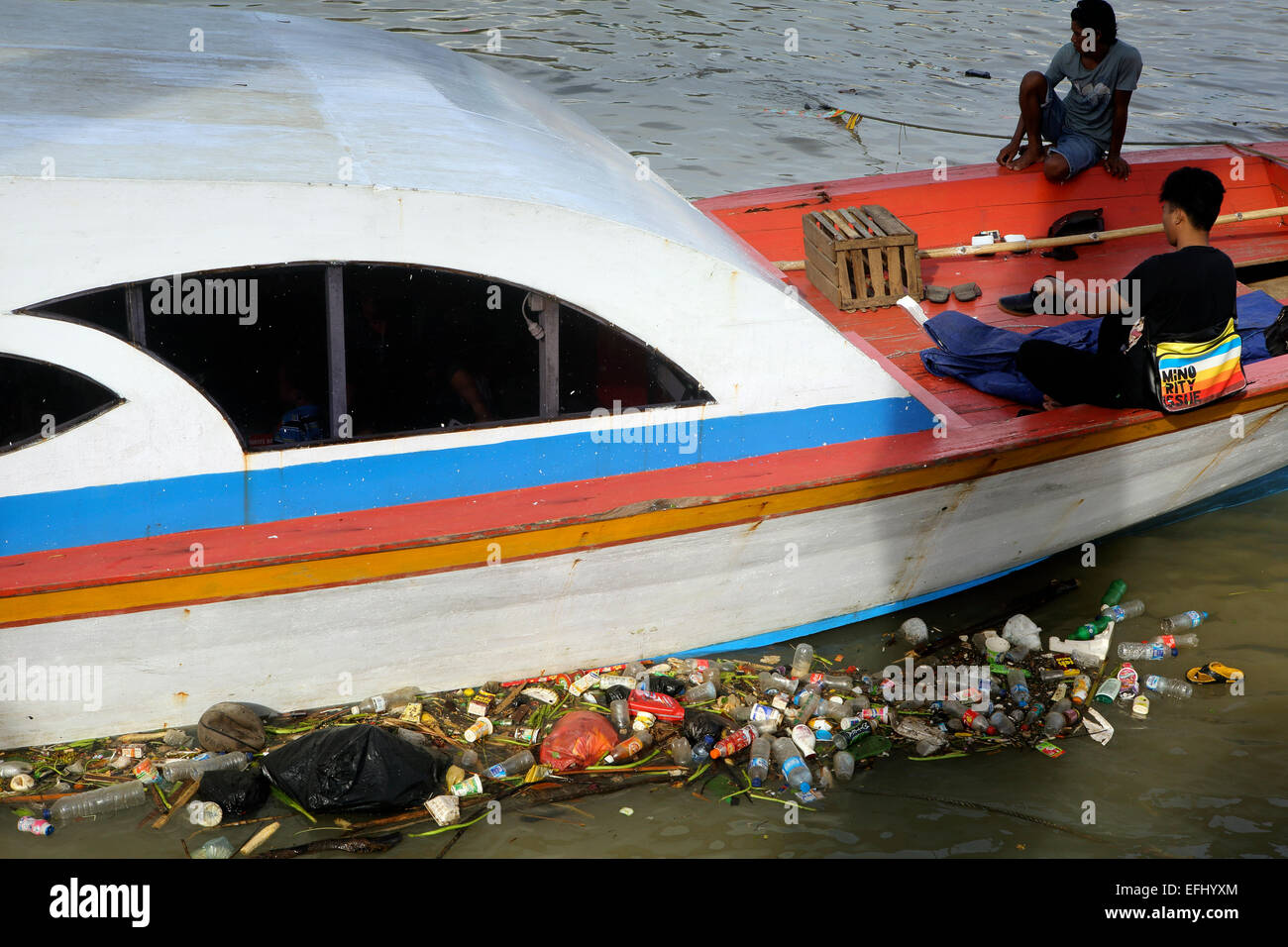 Plastic bottles and other trash floating in Manado River next to wooden ...