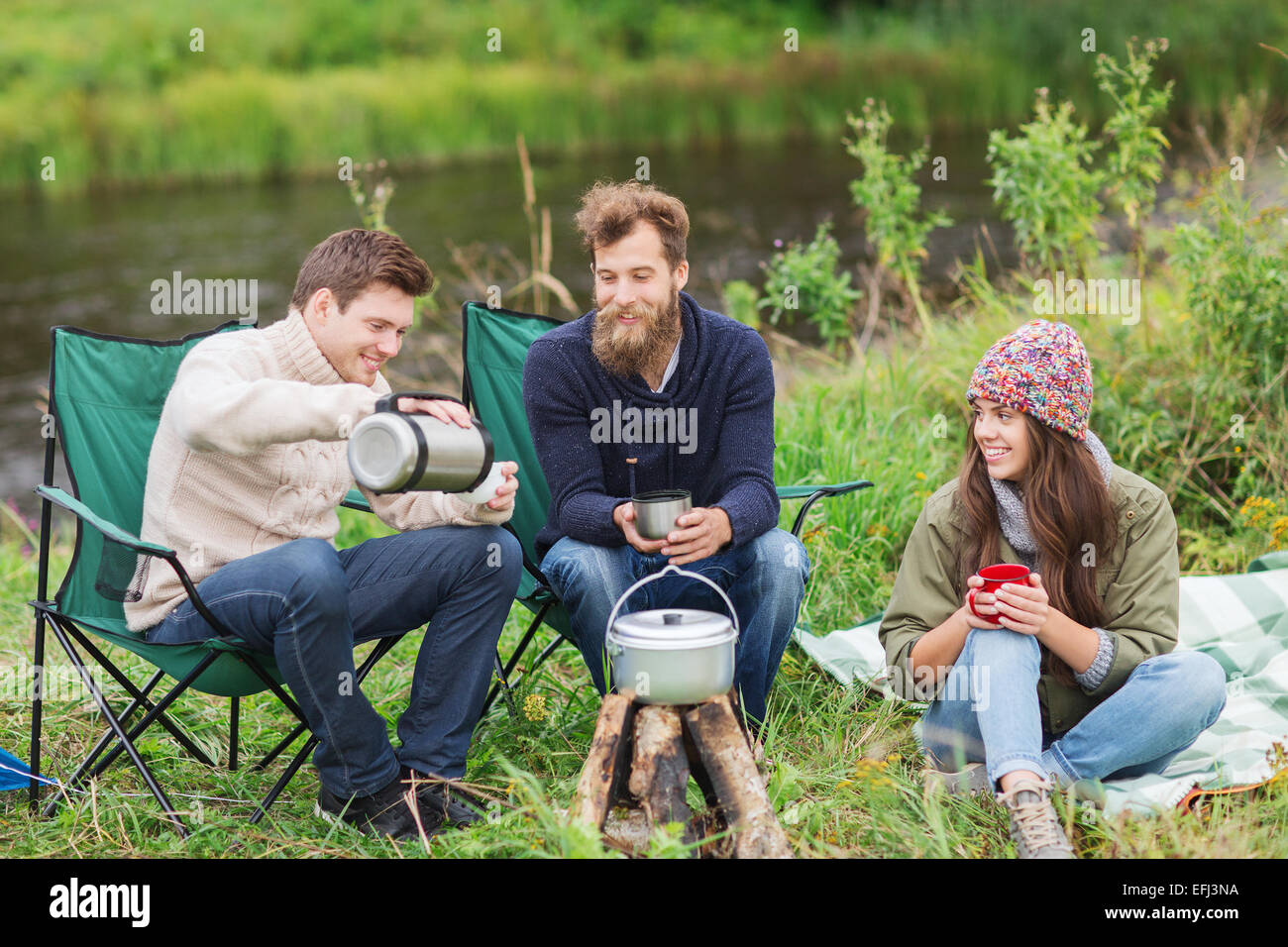 group of smiling tourists cooking food in camping Stock Photo - Alamy