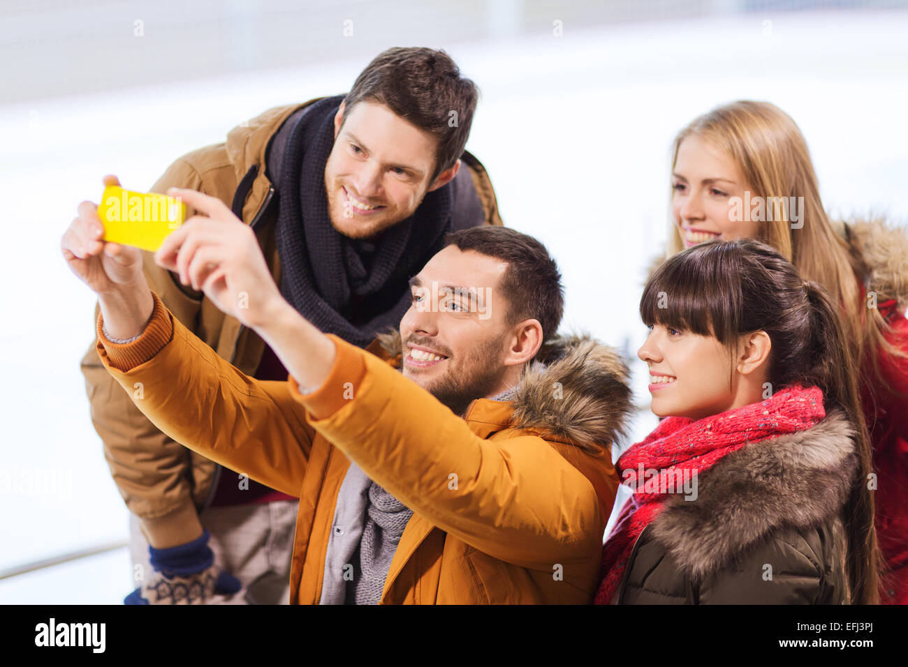 happy friends with smartphone on skating rink Stock Photo - Alamy