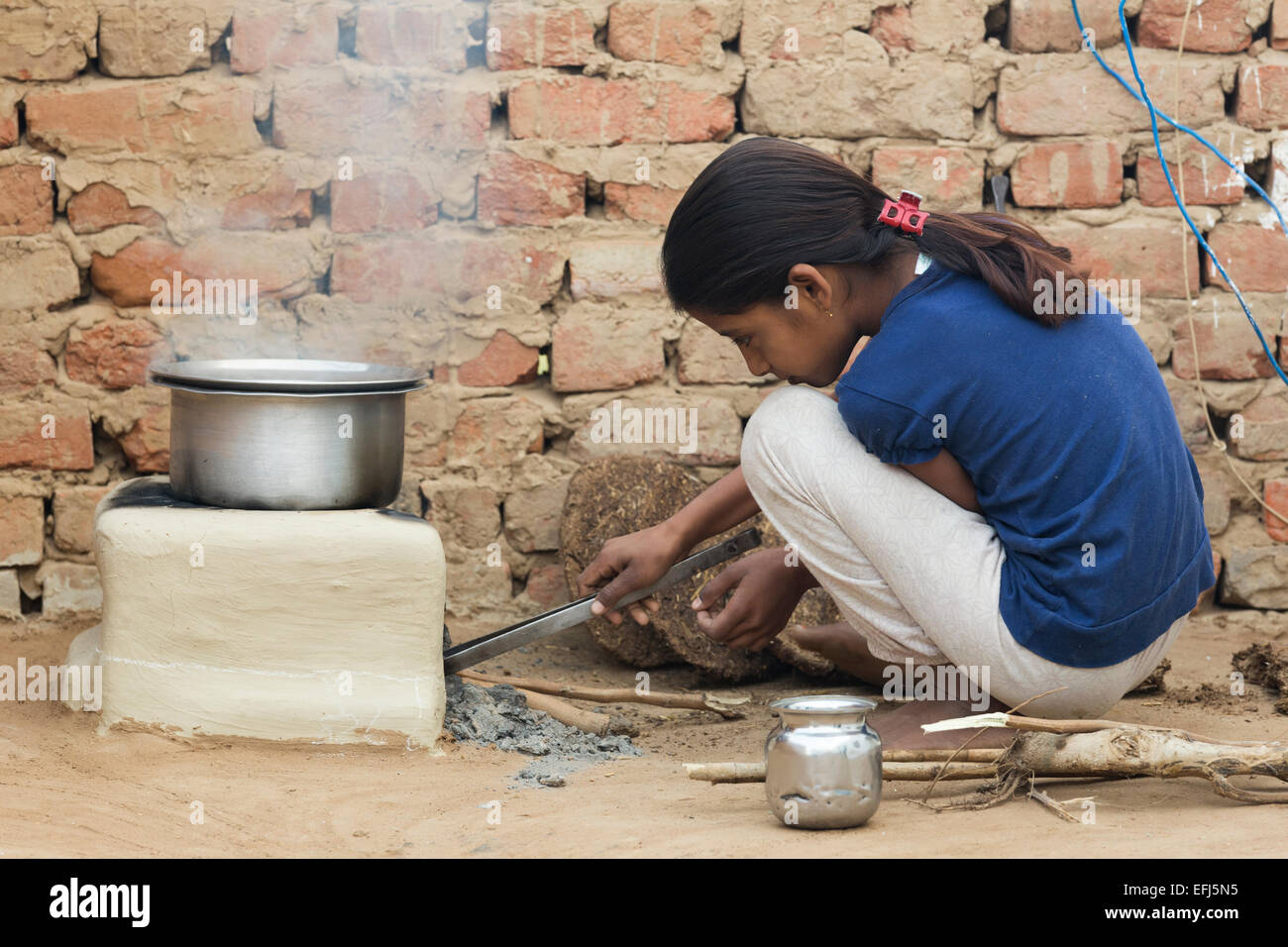 India, Uttar Pradesh, Agra, Indian girl tending to outdoor fire using ...