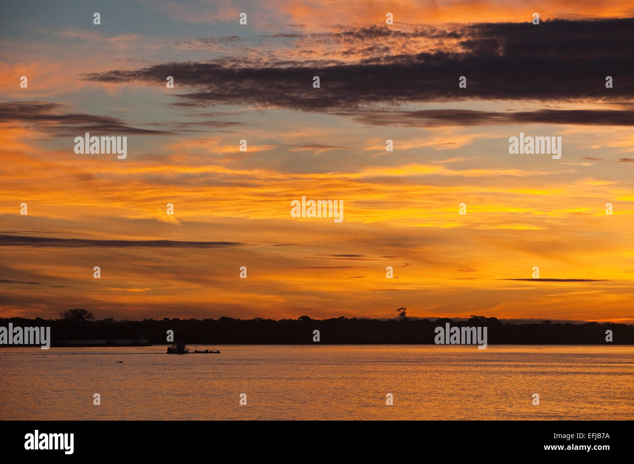 Sunrise over the Amazon River at 6am with far river bank silhouetted ...