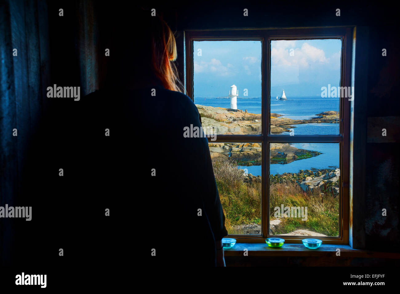 A young woman looking out a window in the nordic archipilago. Looking ...