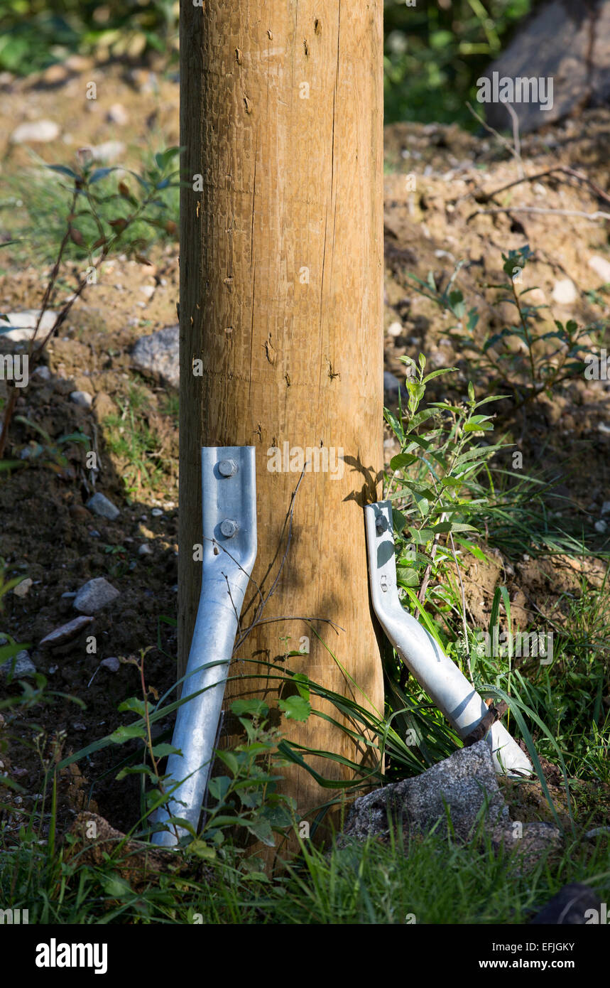 Metal supports supporting wooden electricity pole at rock surface where ...