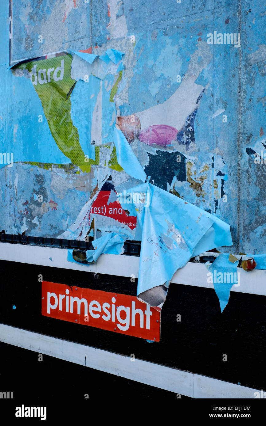 torn and ripped billboard poster hangs down in strips awaiting ...