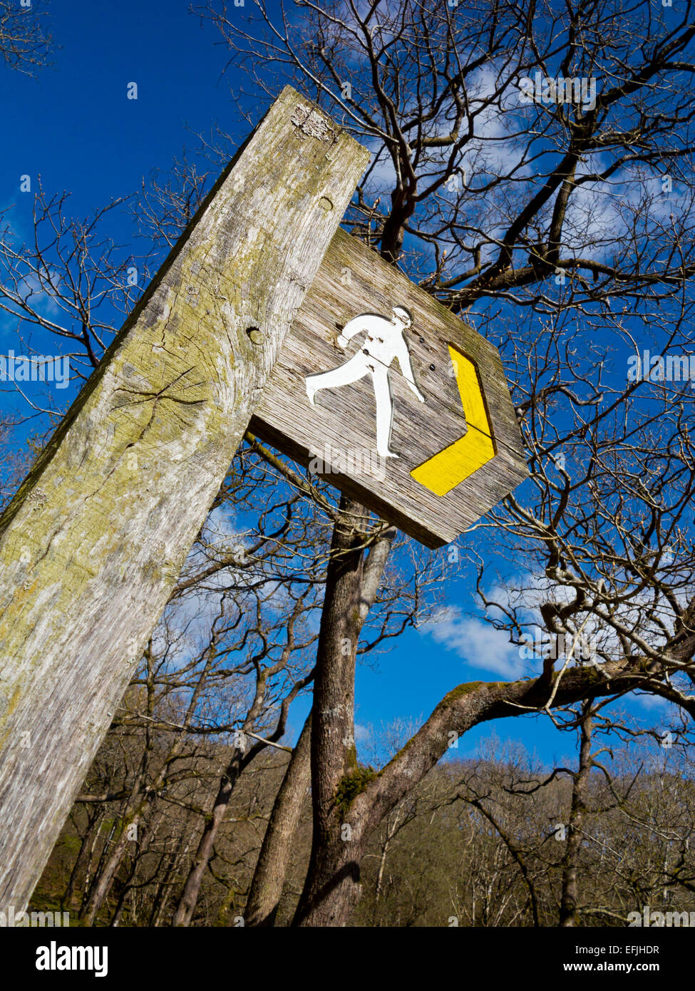 Wooden public footpath sign showing man walking and direction arrow ...