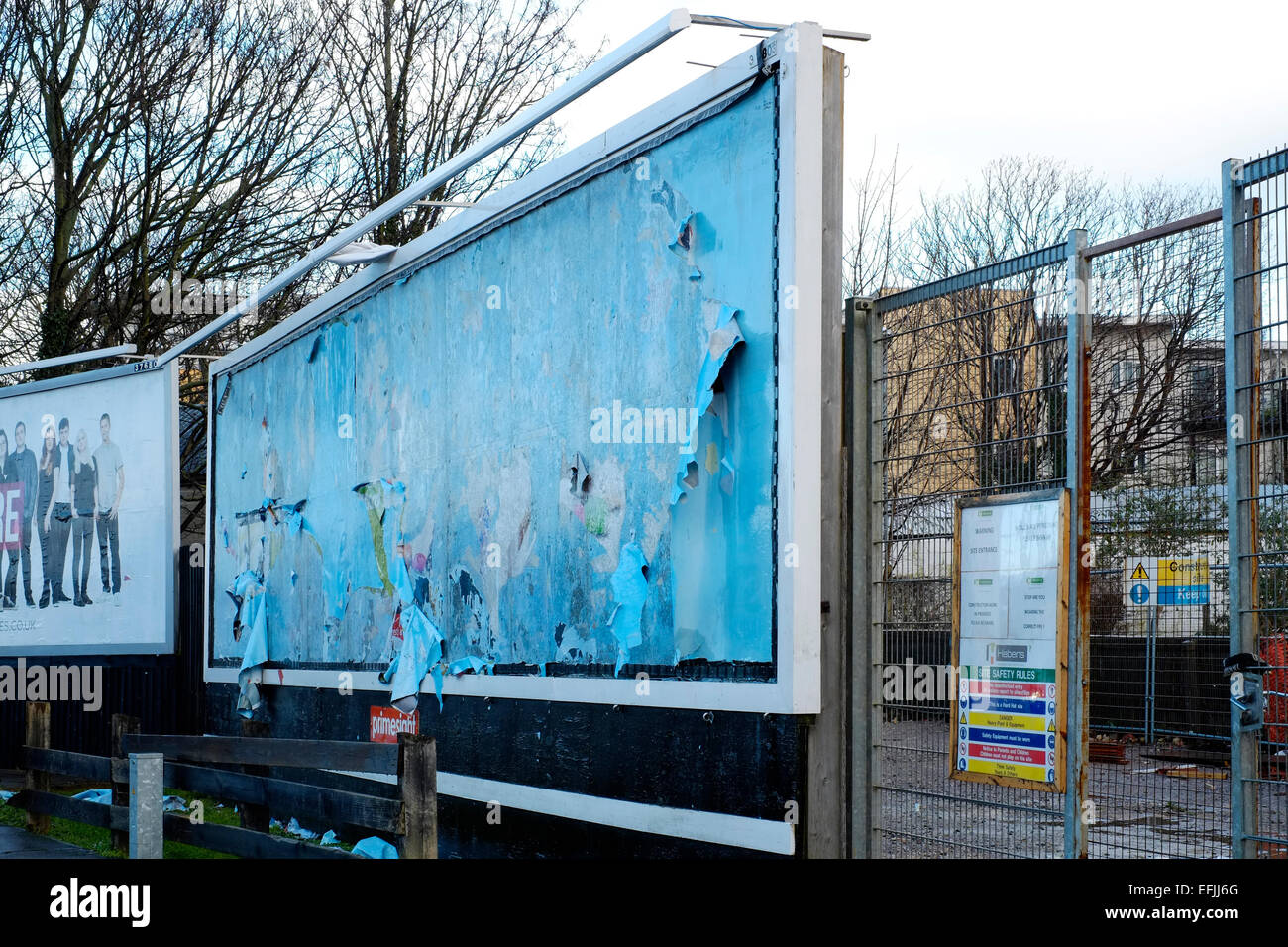 torn and ripped billboard poster hangs down in strips awaiting ...